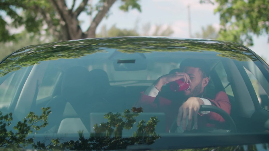Reckless African American man drinking while driving | ClipStock