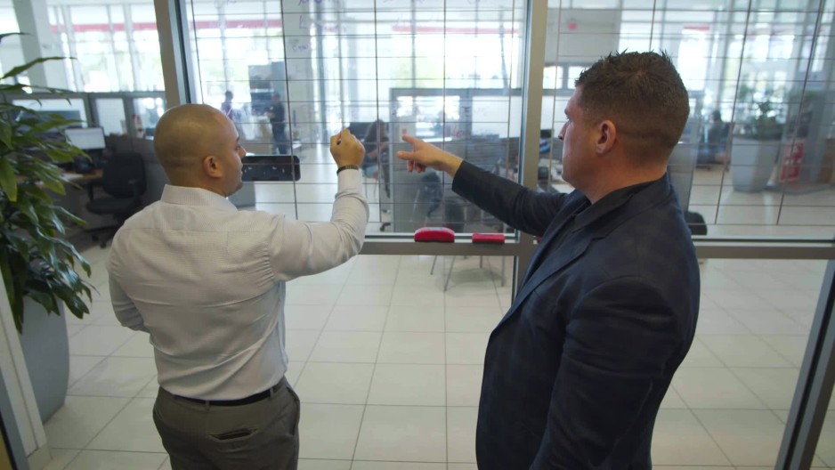 Employee and boss writing work notes on window board in office | ClipStock