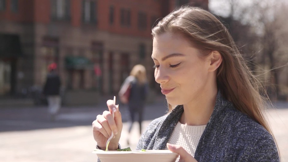 Tight of beautiful Caucasian woman sitting on ledge eating salad in ...