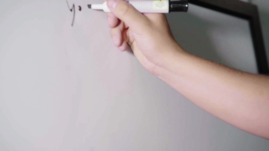 Teacher writes out math equation on whiteboard using black marker ...