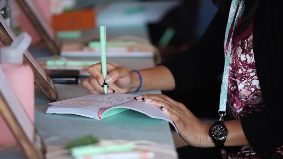 black woman seated in banquet hall writing in notepad in a conference ...