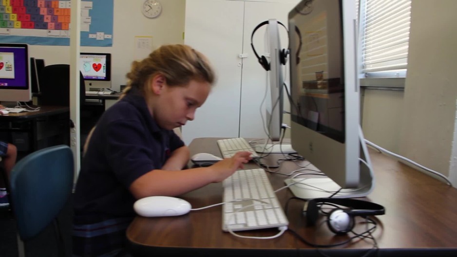 Tracking shot left of two young female students in computer lab using ...