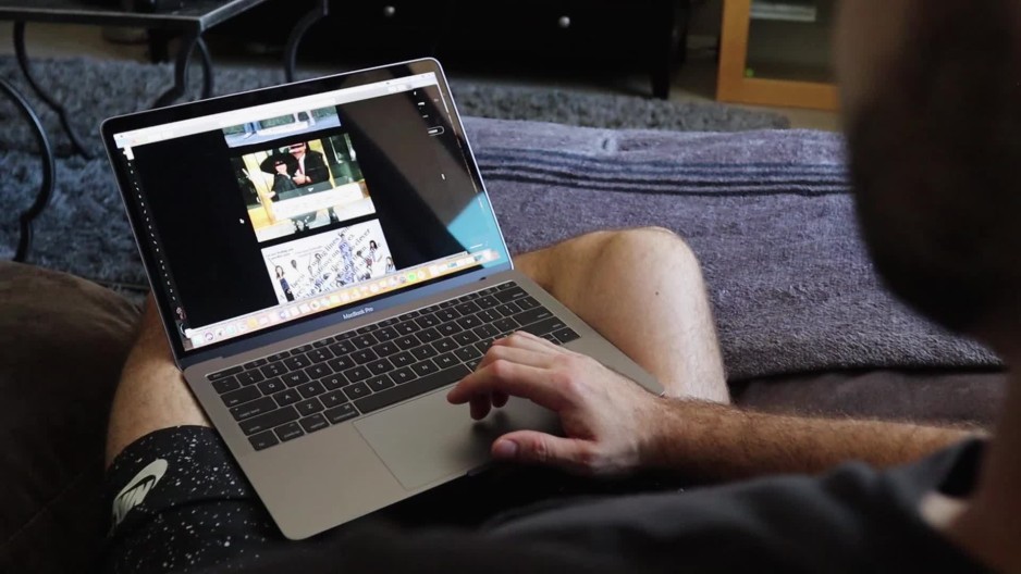 Rotating pan to OTS of man looking at memes on laptop | ClipStock