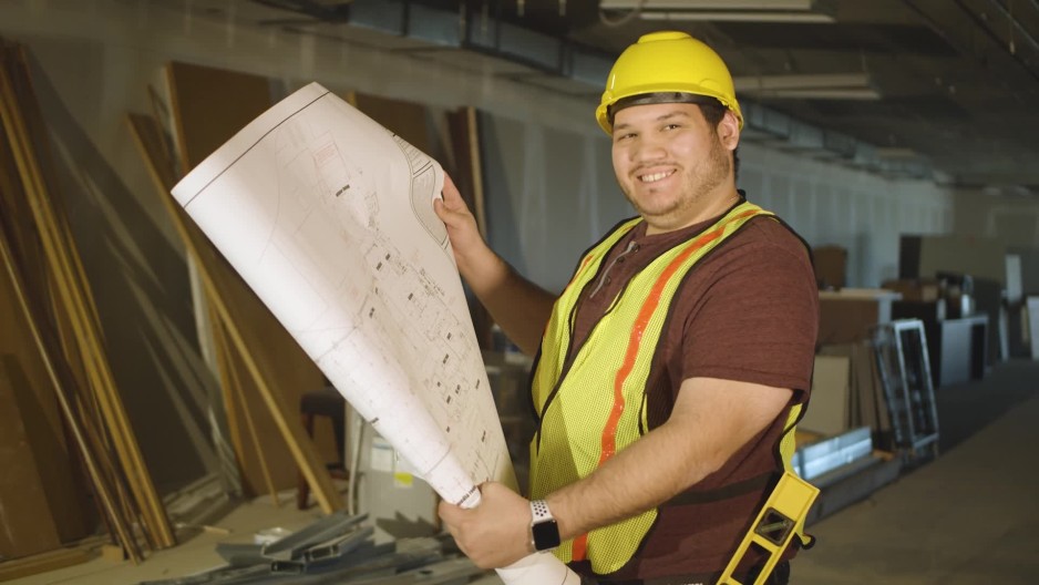 Construction worker in yellow vest and helmet reading blueprints and ...