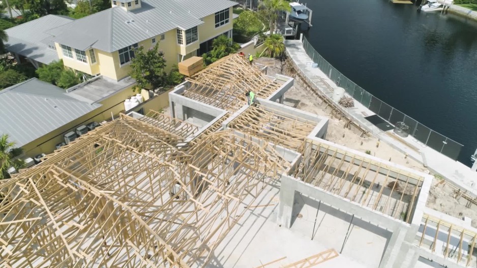 Slow rotating view of construction workers building roof framework of ...