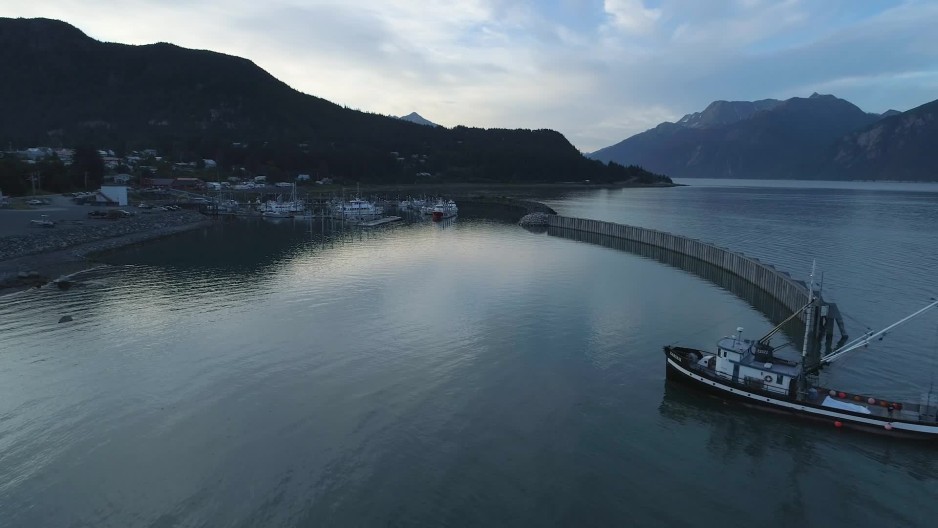 Aerial pull back of boat heading into harbor | ClipStock