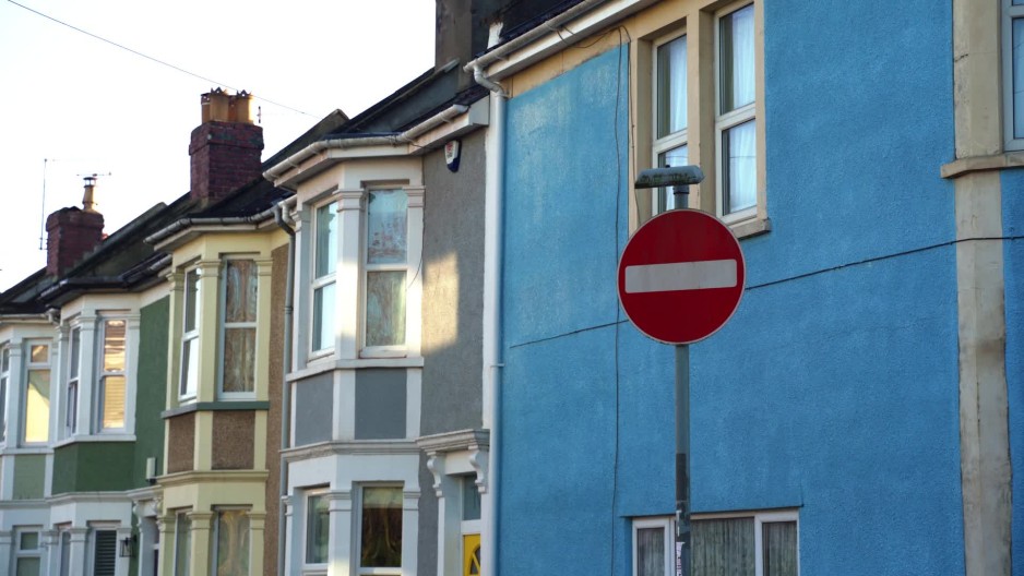 No entry sign posted on metal pole in front of buildings | ClipStock