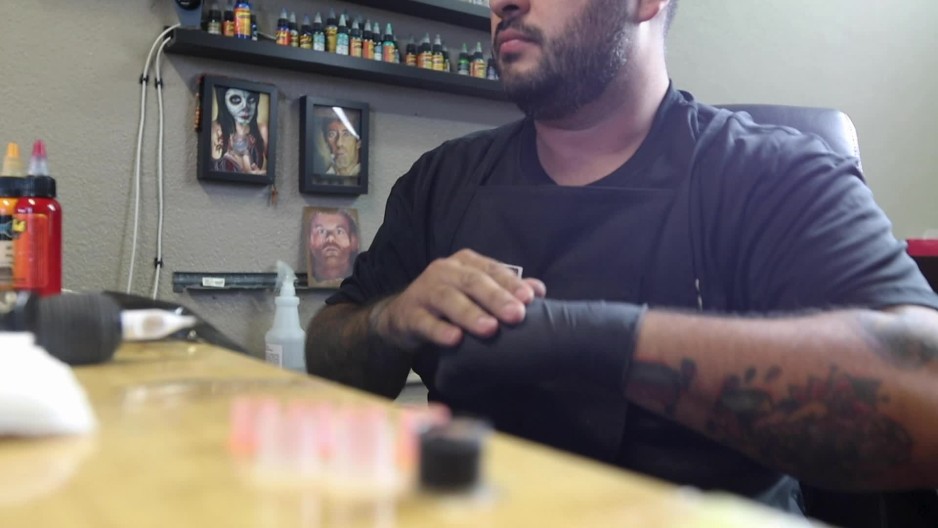 Tattoo artist setting up workspace before tattooing client | ClipStock