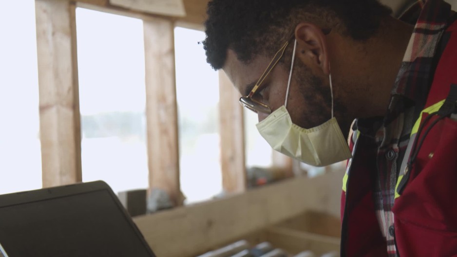African American blue collar worker wearing face mask using laptop ...