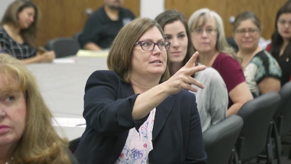 medium shot of woman asking a question to presenter in conference room ...