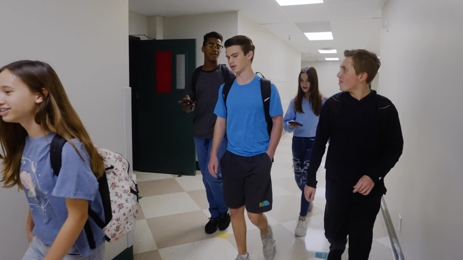 Kids in middle school walking through hallway to class together | ClipStock
