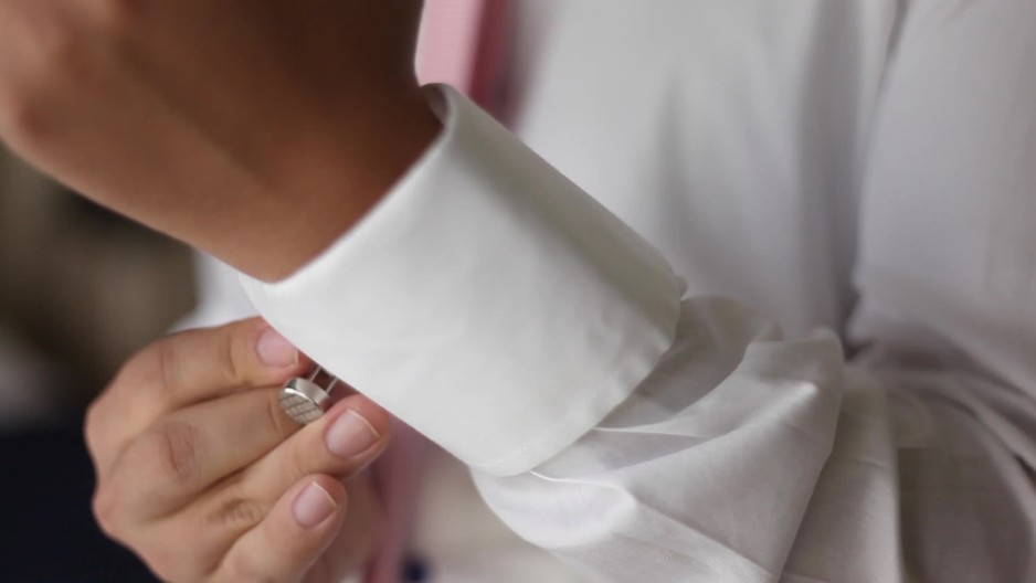Close up of hand fitting on silver cufflink | ClipStock