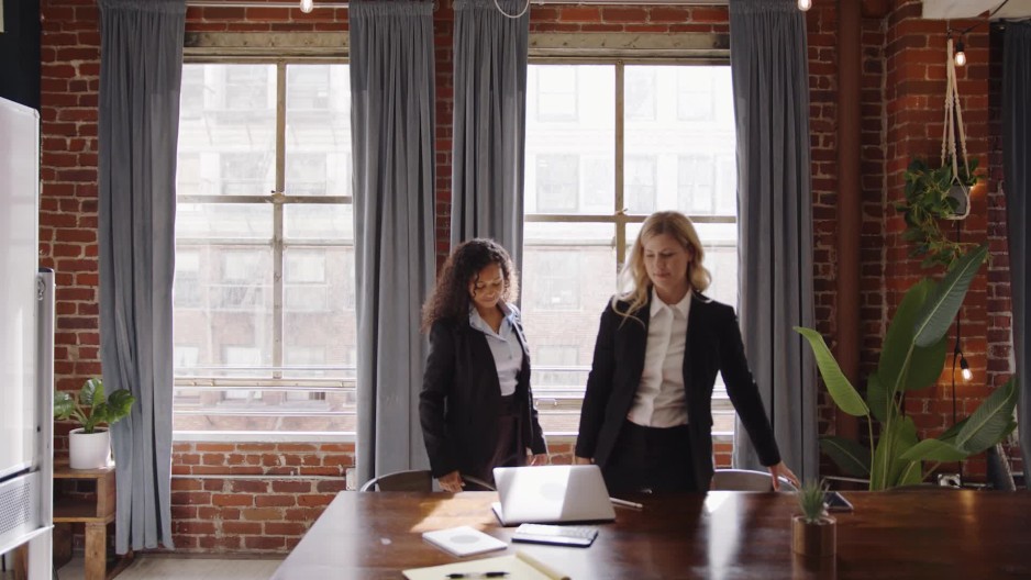Diverse pair of businesswoman walking into conference room and shaking ...