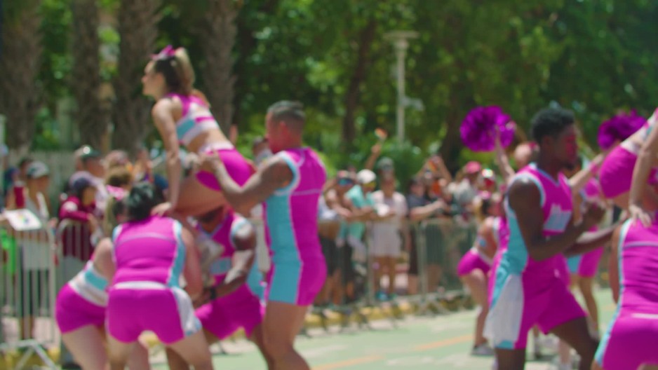 Cheerleaders Performing Routine On Street In Front Of Audience During Outdoor Parade Clipstock 