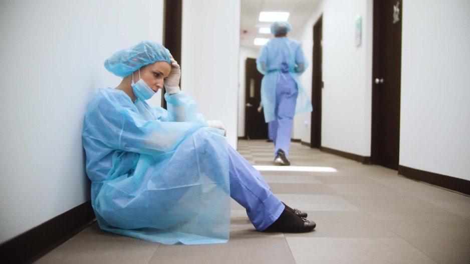 Distraught surgeon shaking head and sitting in hallway | ClipStock
