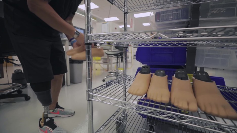 Man taking prosthetic feet from rack in laboratory | ClipStock