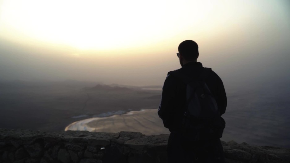 Man standing behind barrier on edge of cliff | ClipStock