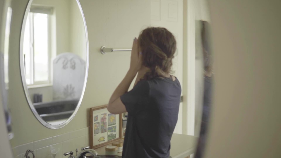 adolescent girl wiping her face in the mirror in the bathroom slow ...